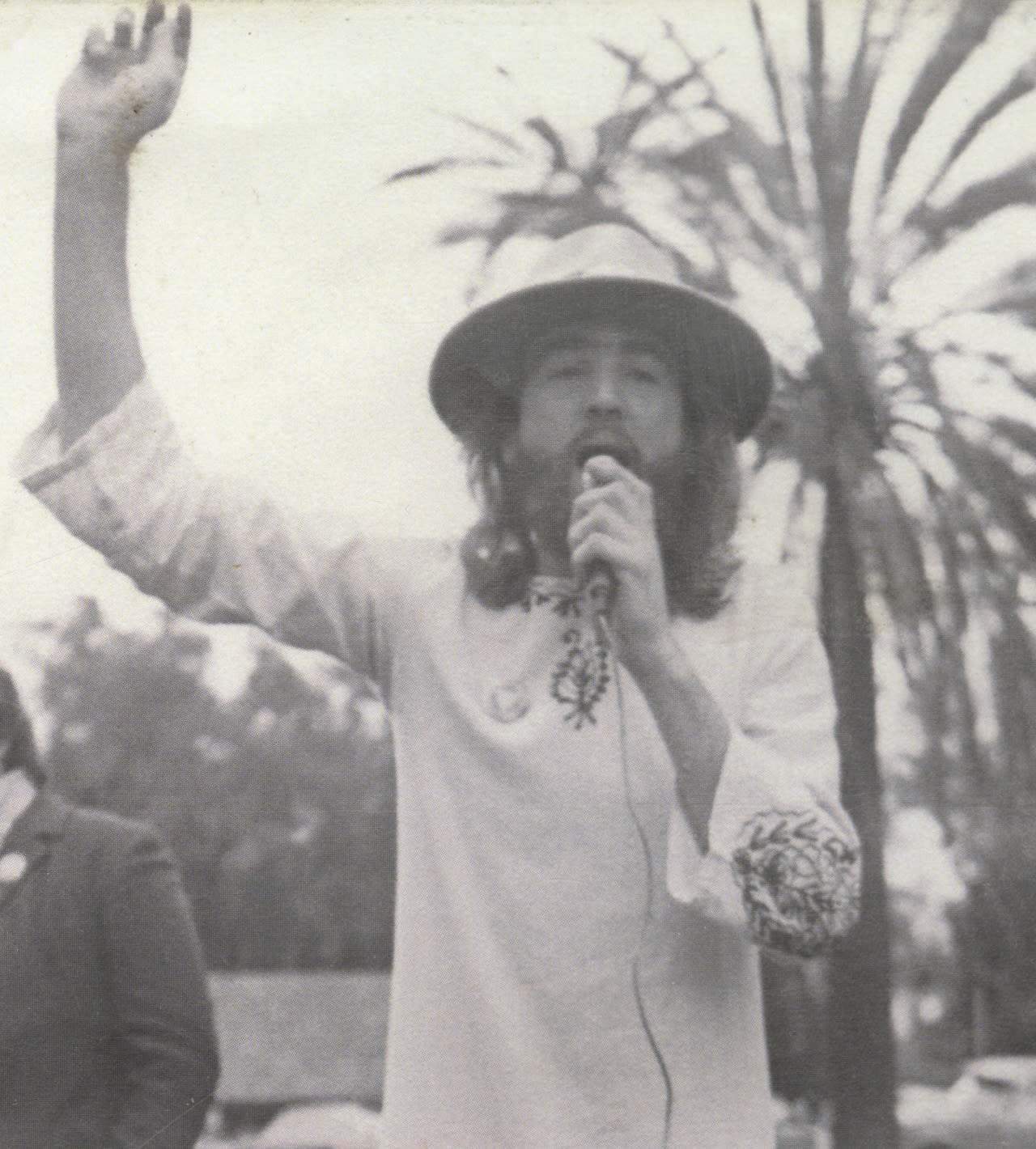 Will Sergeant speaks into a microphone with his right arm raised. Black ...