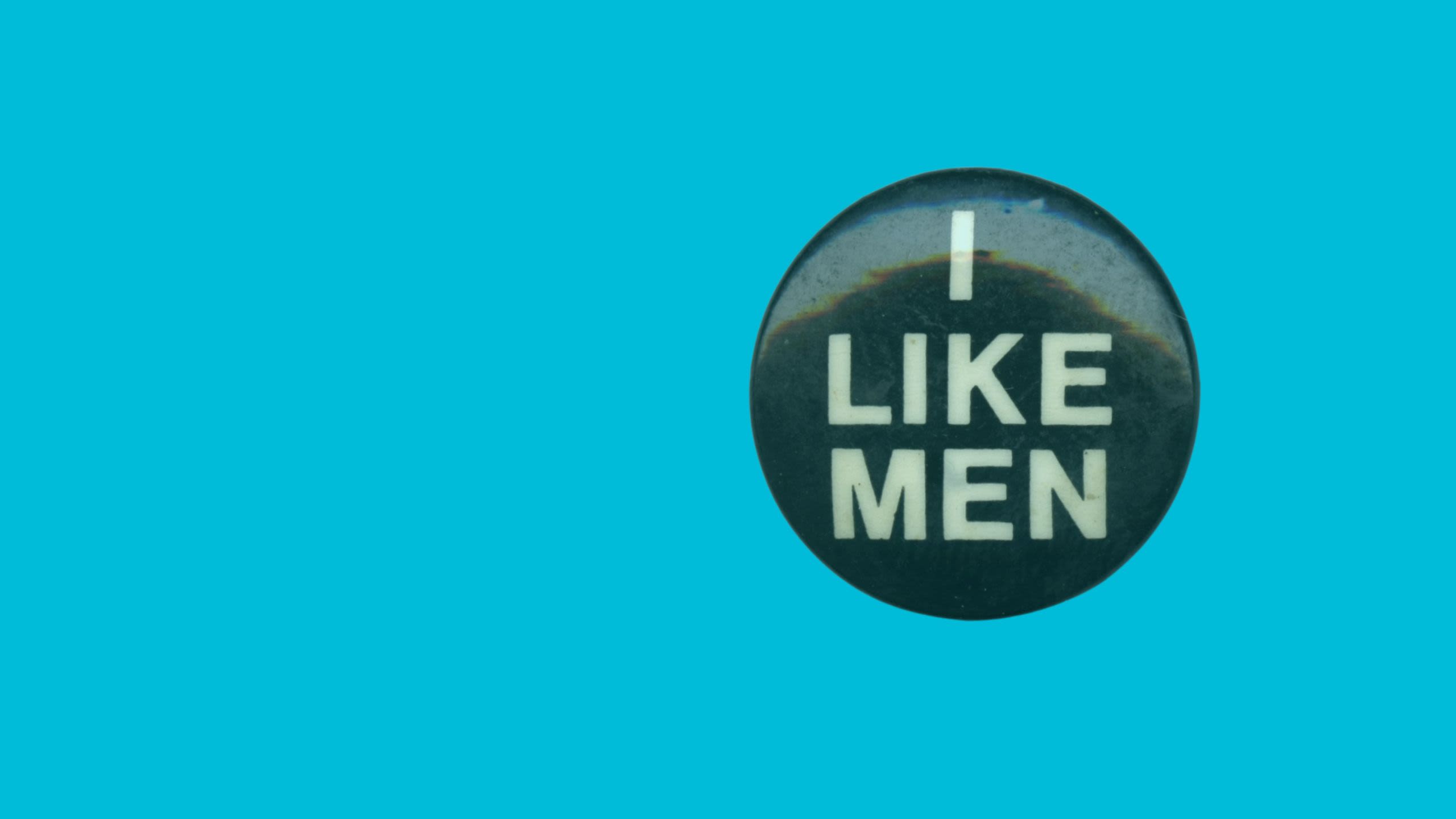 A round black badge with white text ‘I LIKE MEN’ against a light blue ...