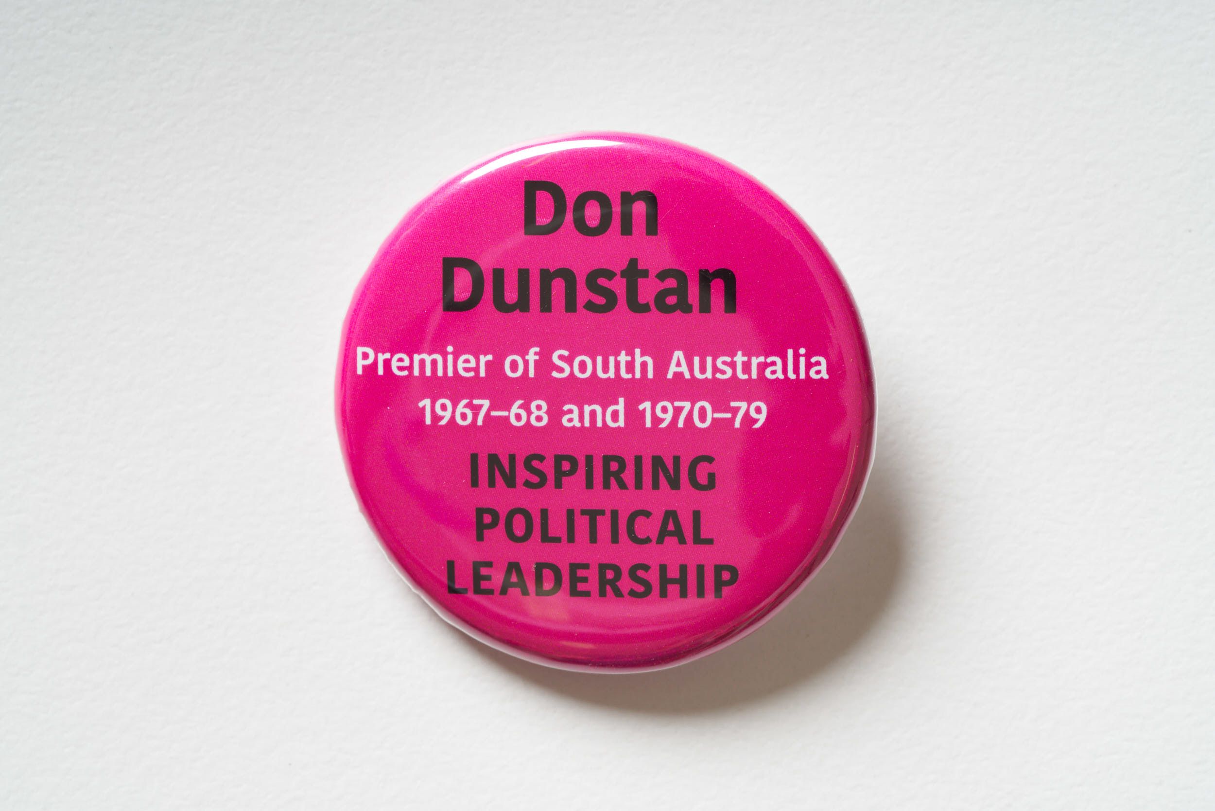 A round pink badge that reads ‘Don Dunstan, Premier of South Australia ...